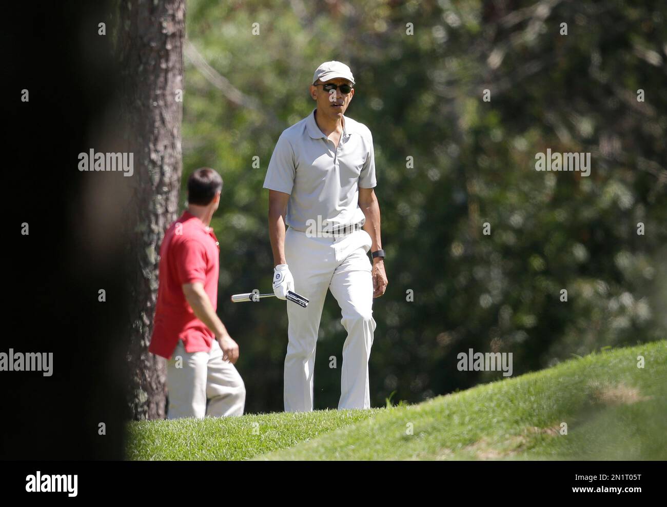 President Barack Obama, right, carries a golf club as he approaches a ...