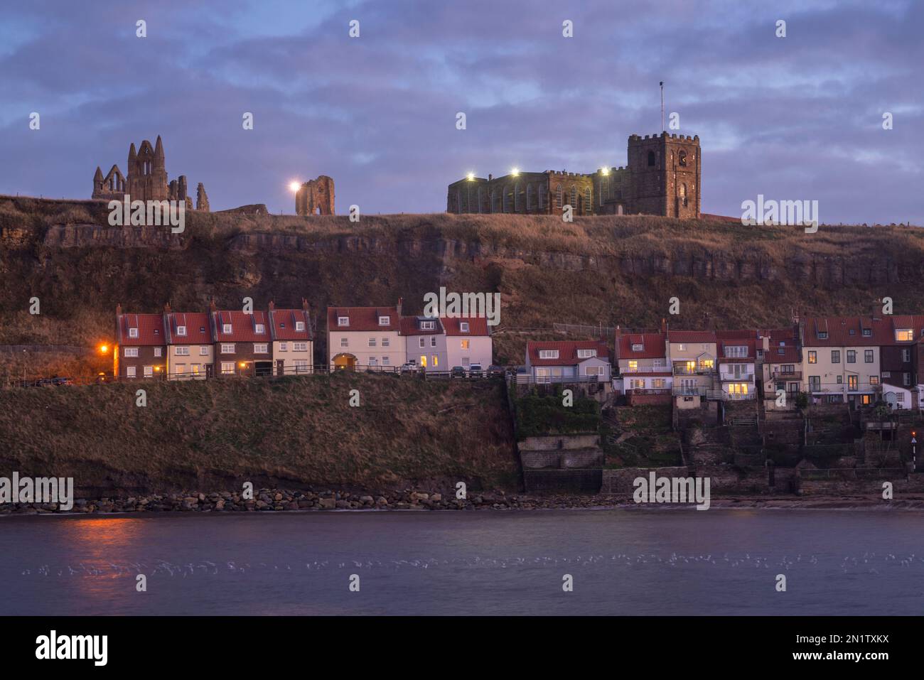 Dusk falls over Whitby harbour and the Church of St. Mary, North ...