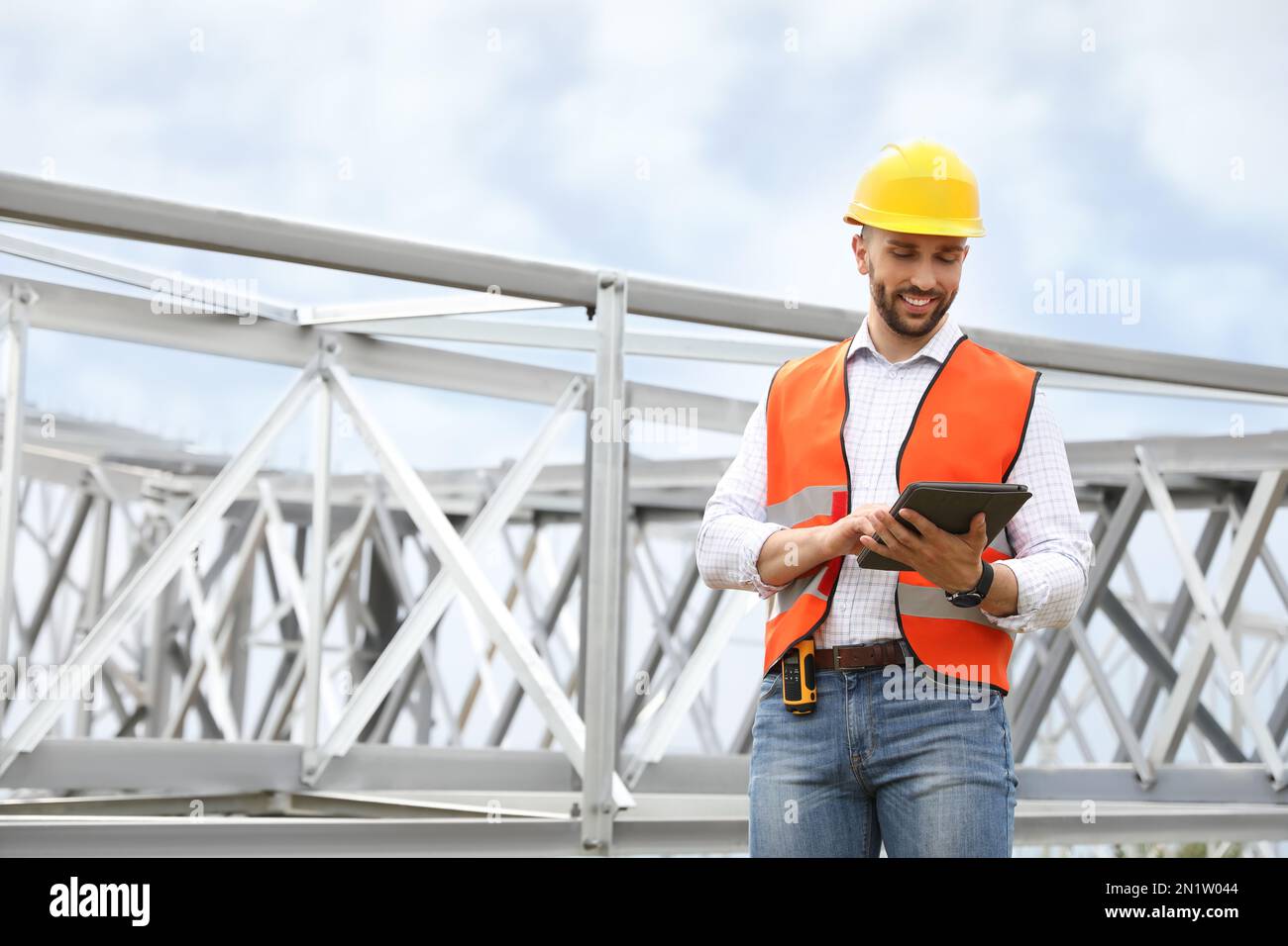 Professional engineer with tablet near high voltage tower construction ...