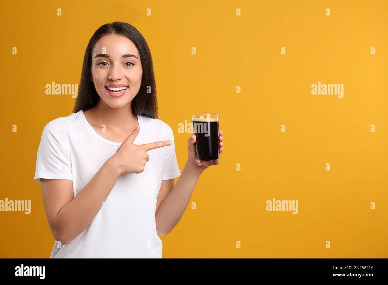 Beautiful woman with cold kvass on yellow background. Traditional ...