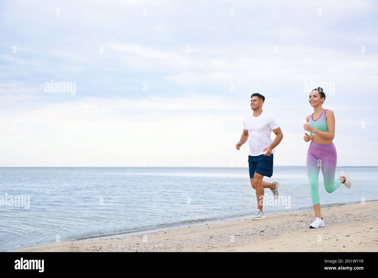 Couple running together on beach, space for text. Body training Stock ...
