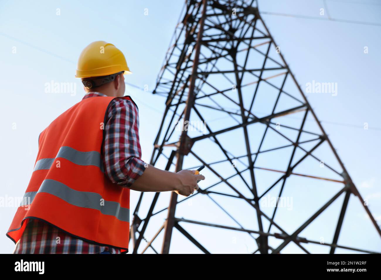 Electrical engineer with walkie talkie near high voltage tower, low ...