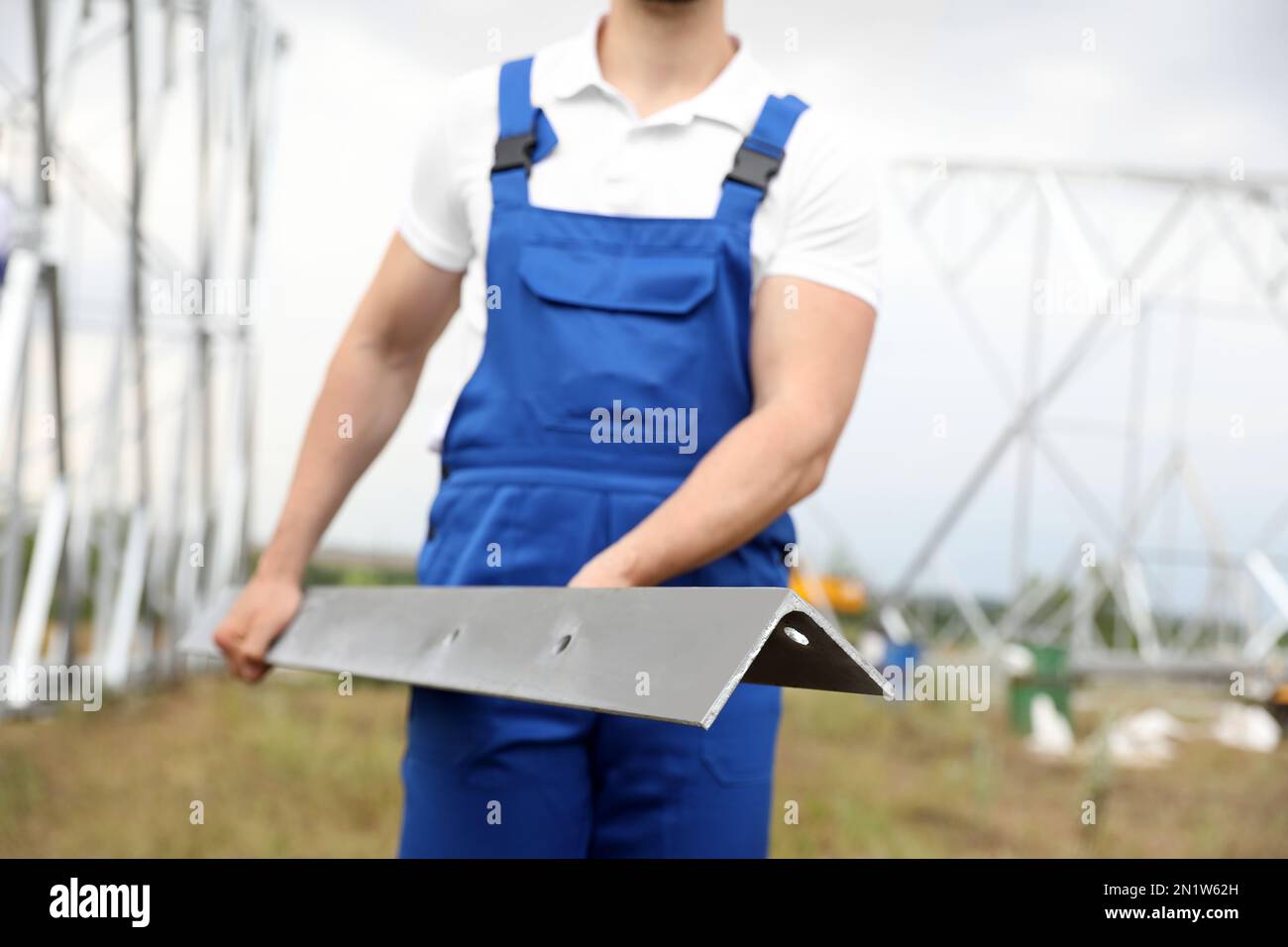 Worker with detail from high voltage tower construction on building ...