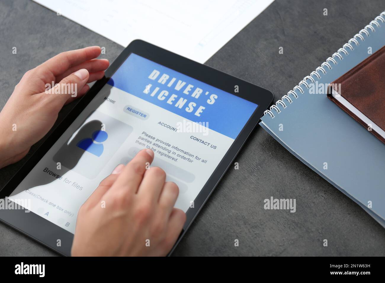 Person using tablet to fill driver's license application form at grey table, closeup Stock Photo ...