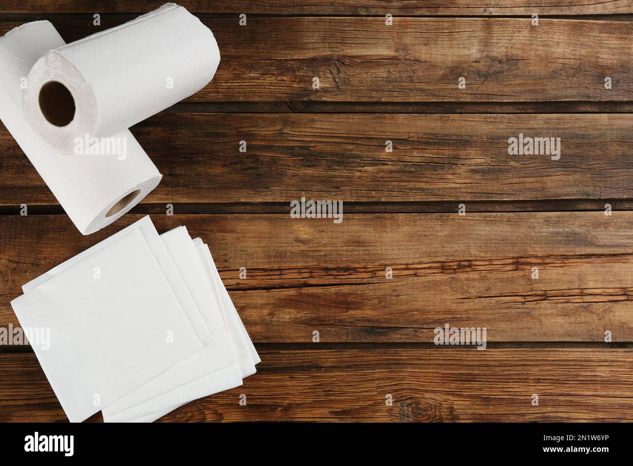 Clean napkins and rolls of paper towels on wooden table, flat lay ...