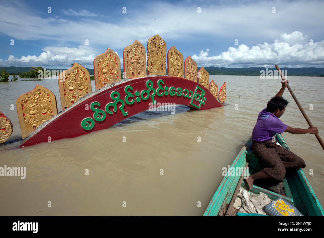 A man rows his boat by the entrance signboard of Kalay township ...