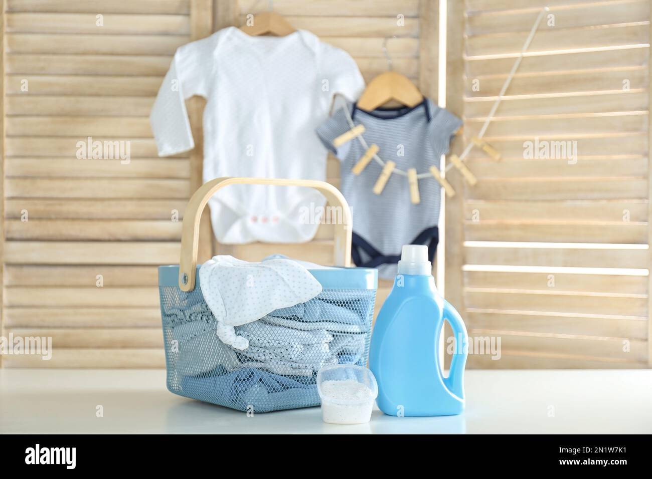 Basket with baby laundry, bottle of detergent and washing powder on ...