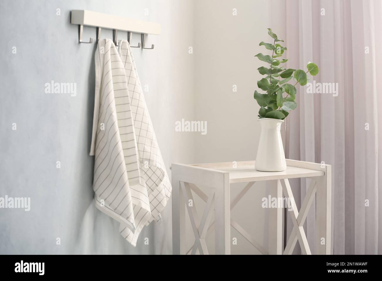 Hanger with kitchen towels and beautiful plant on table indoors ...