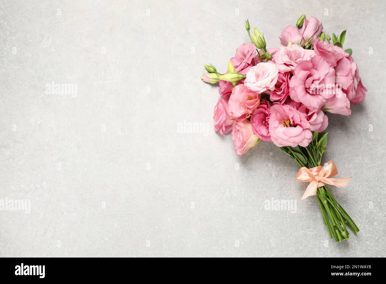 Beautiful bouquet of pink Eustoma flowers on light grey background, top ...