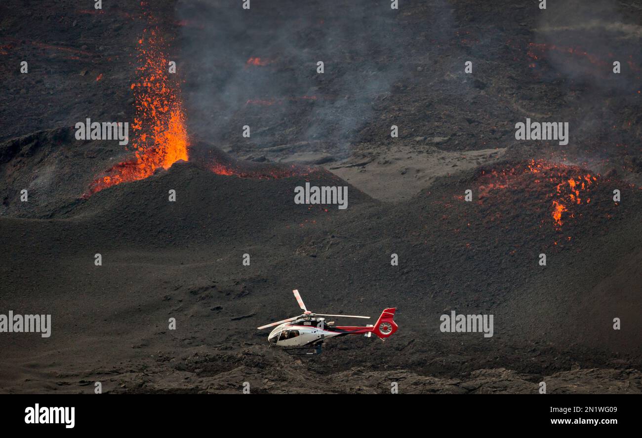 A helicopter flies past as lava erupts from the Piton de la Fournaise ...