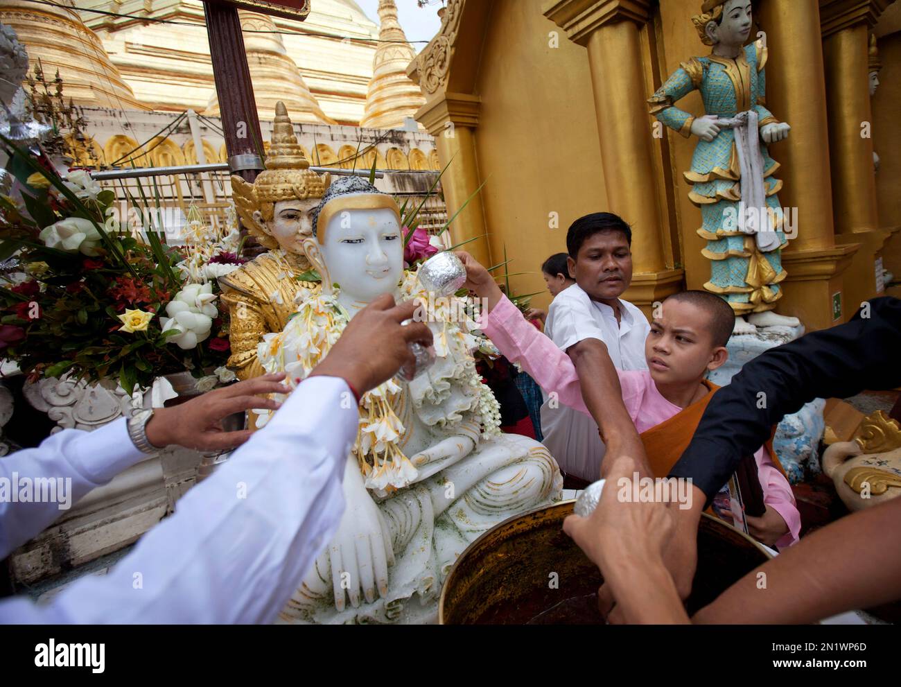 Buddhist devotees including a Buddhist nun pour water on a Buddha ...
