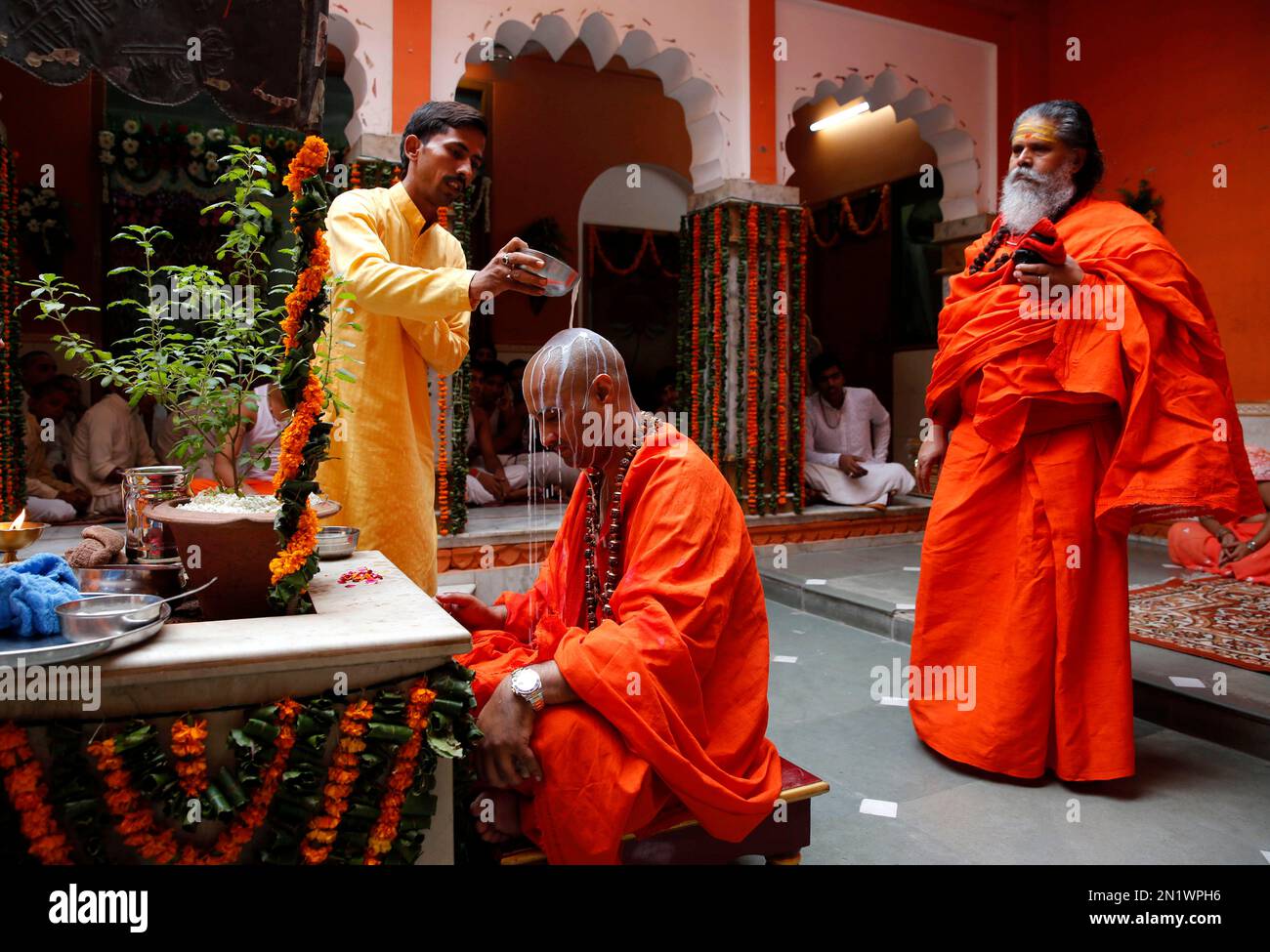 A devotee pours milk on the head of his Guru as a mark of respect on ...