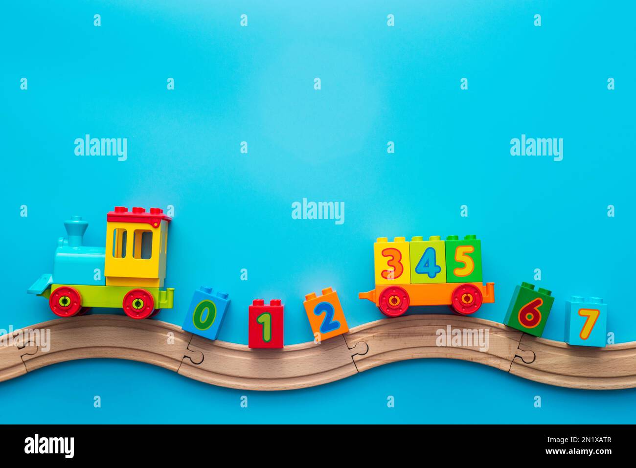 Colorful toy train locomotive with numbers on wooden railway on blue ...