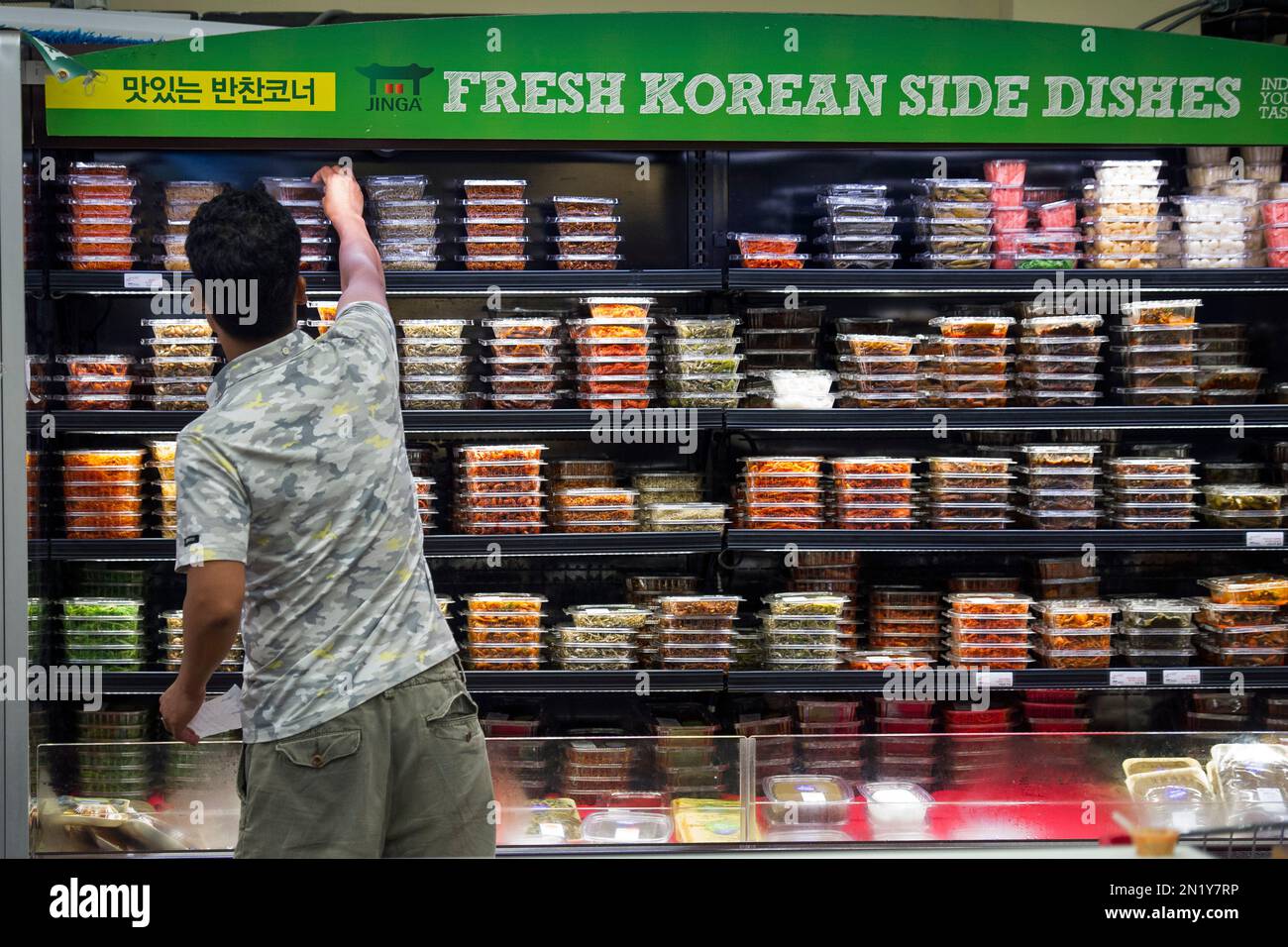 A man reaches for a prepared food item in a refrigerated display at the ...