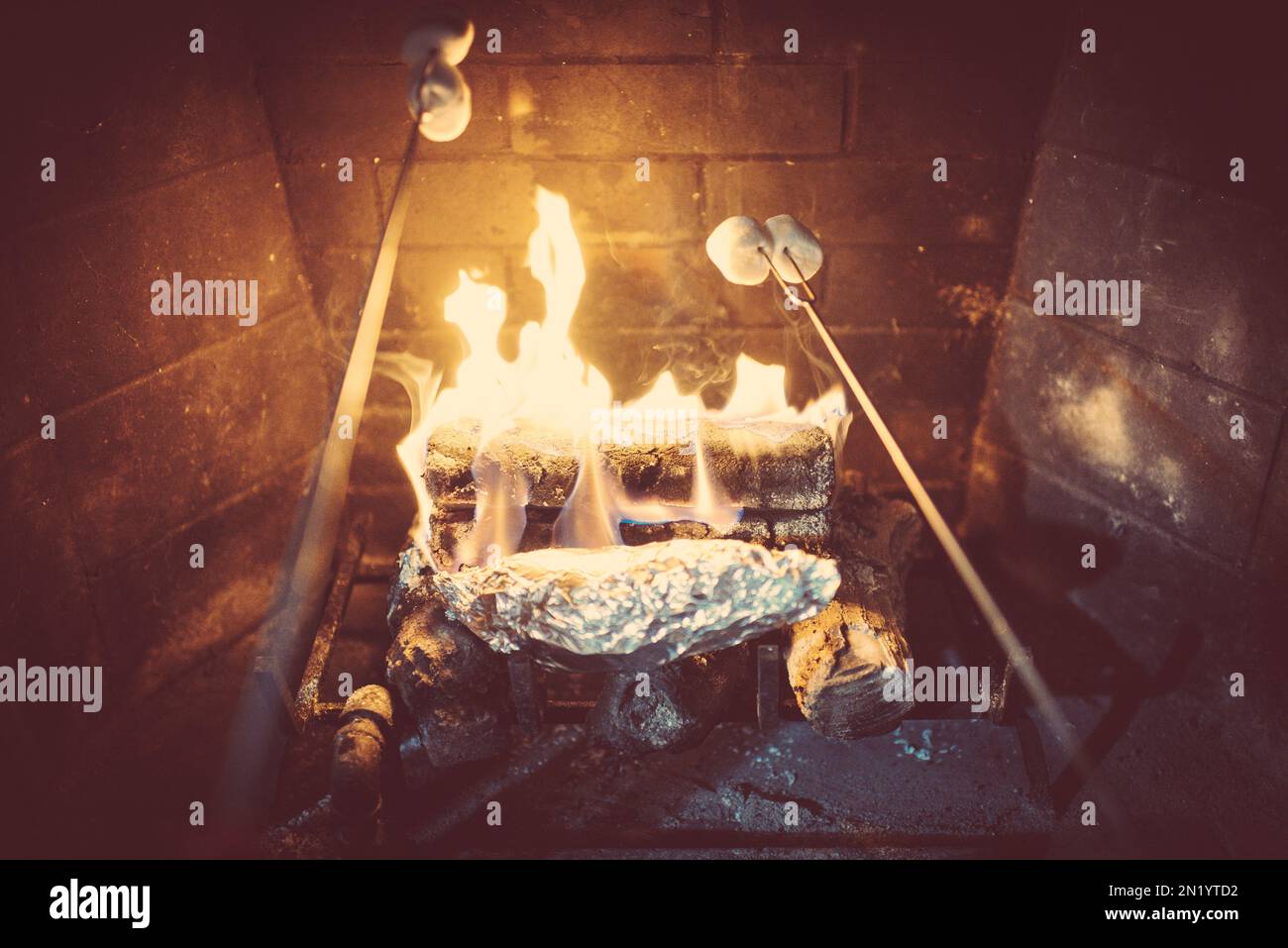 Baking sweet potato and roasting marchmellows in fire place Stock Photo ...