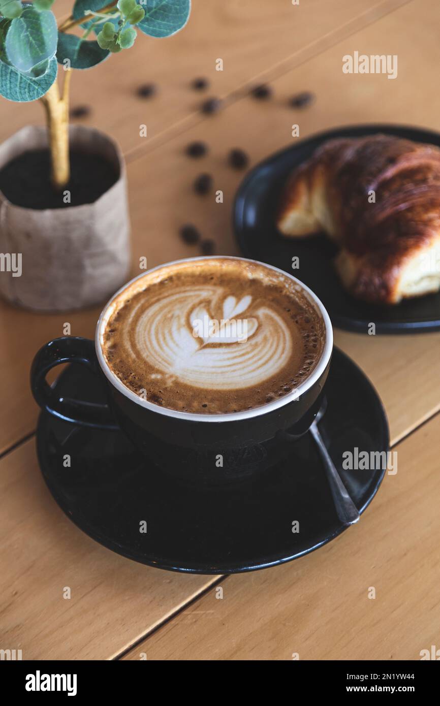 Coffee prepared by a barista in a black cup on a restaurant table. Food ...