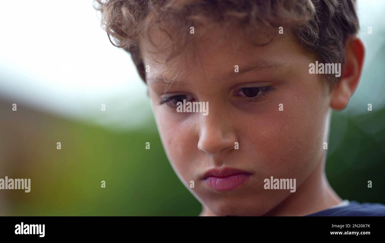 One concentrated little boy face closeup. Focused child with serious ...