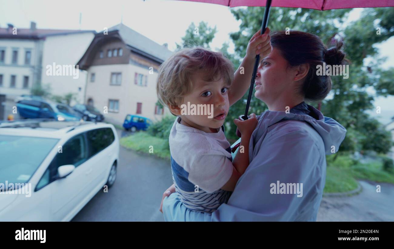 Mother and child son under umbrella during rainy day. Parent and little ...