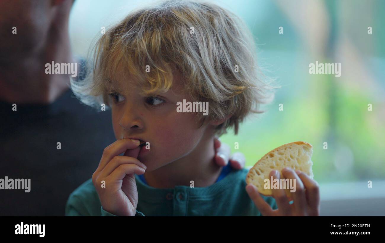 Pensive child eating bread sitting at restaurant thoughtful little boy ...