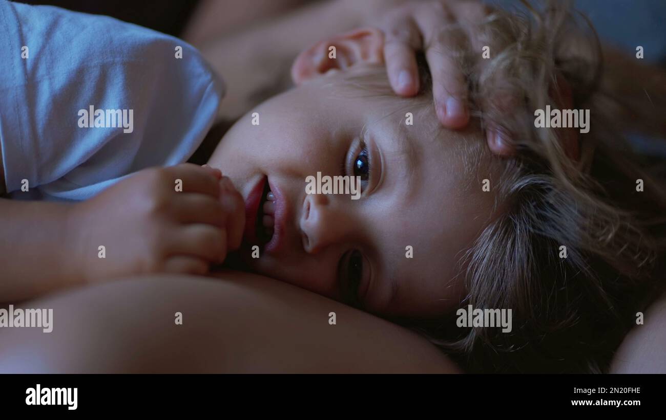 Mother caresses child blond hair. Little boy laying on mom leg ...