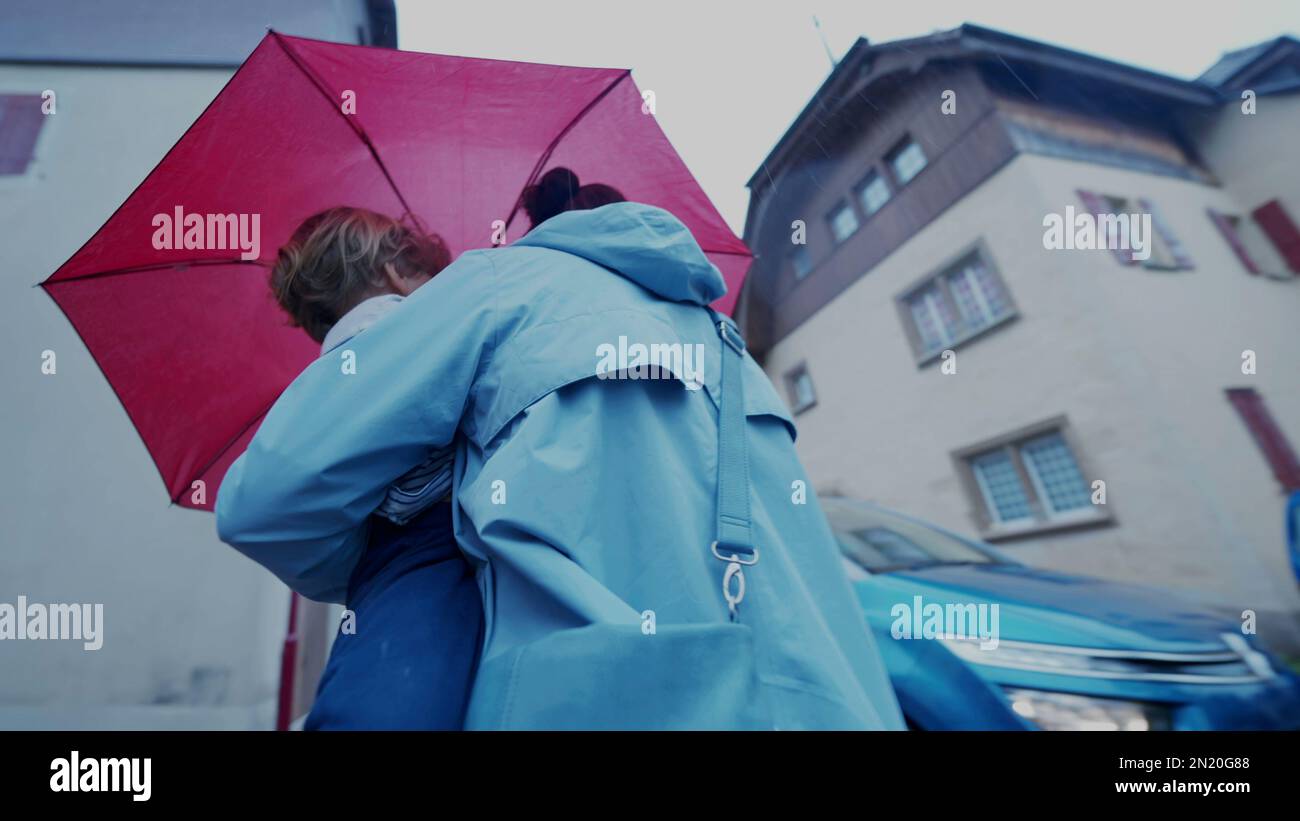 Mother holding umbrella walking outside with child in arms while ...
