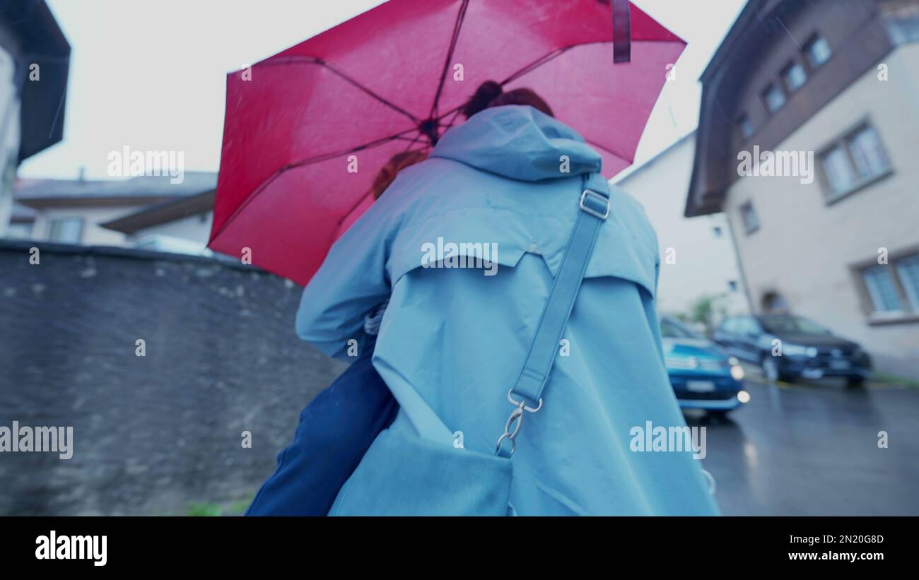 Mother holding umbrella walking outside with child in arms while ...