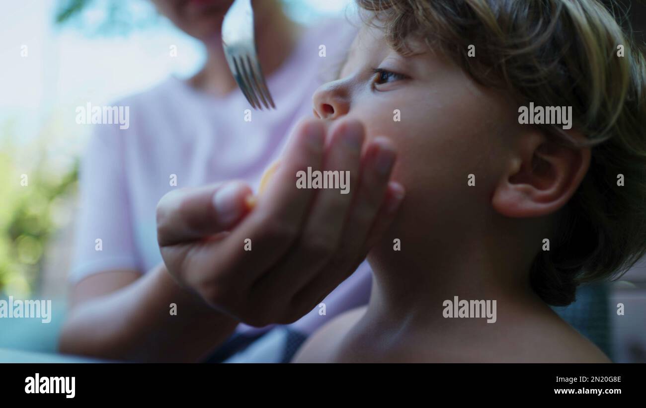 Mother feeding pasta to little boy. Child eating spaghetti for lunch ...