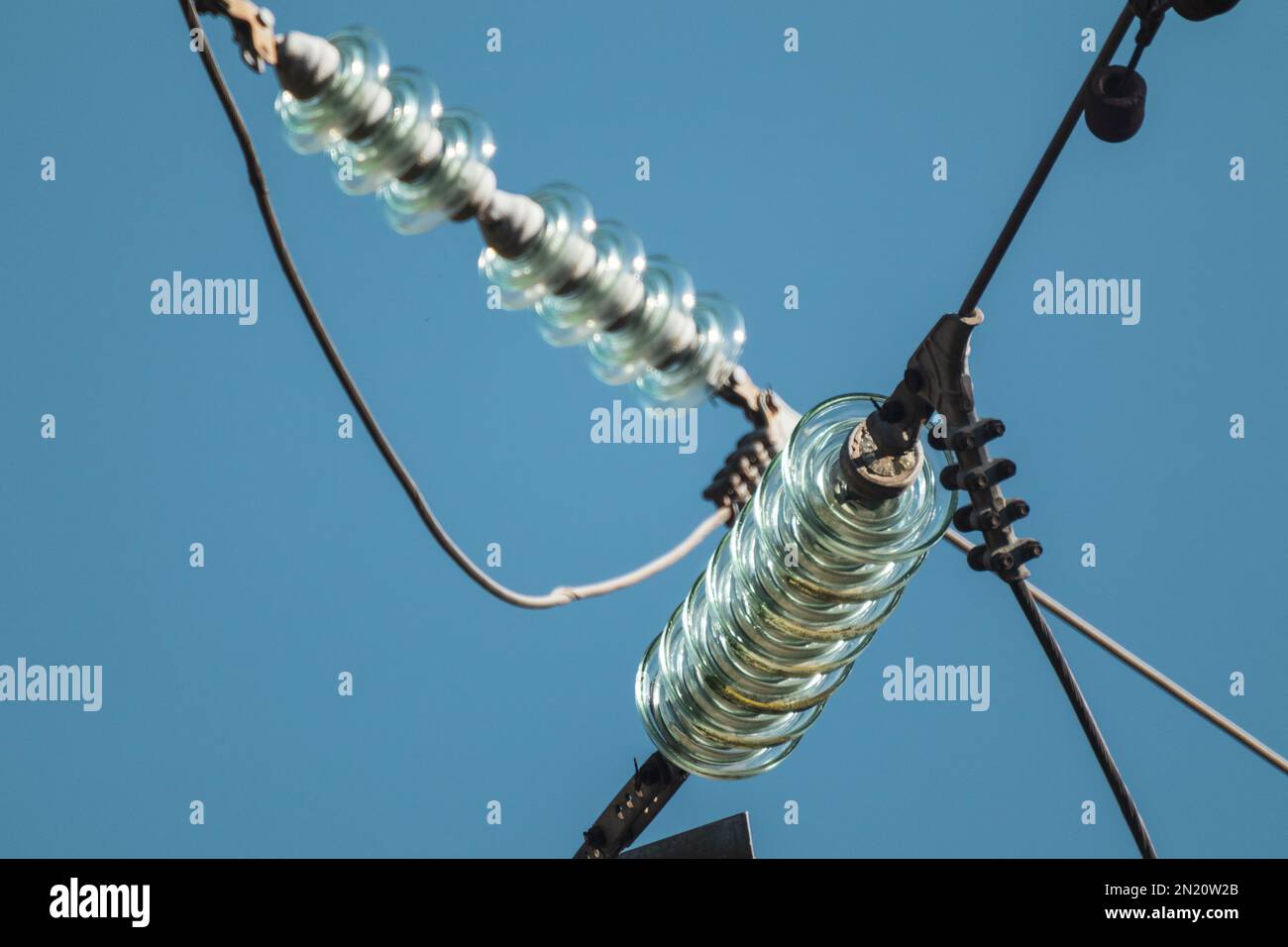 High voltage glass insulators on electric transmission line close-up ...