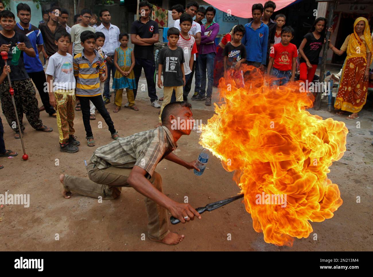 Residents gather to watch as an Indian man displays his fire stunt ...