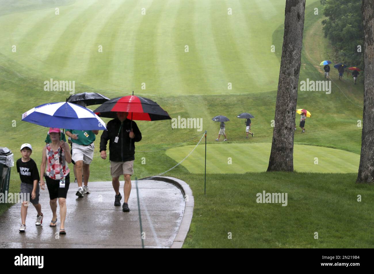 Spectators return to the clubhouse during a rain delay at the third ...