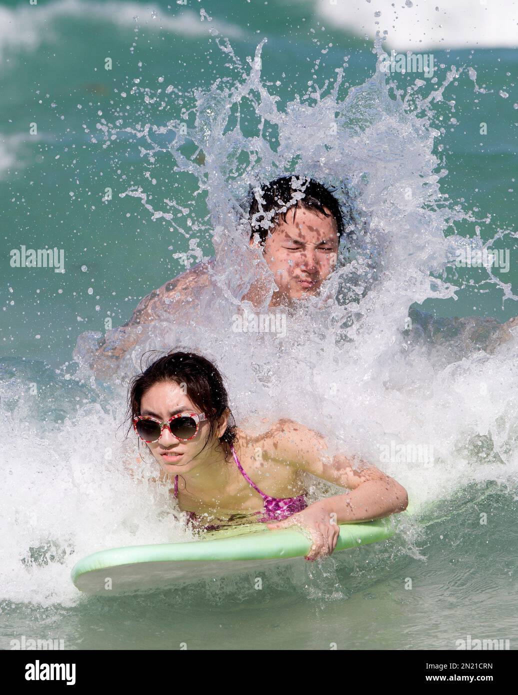Xiaohui Liu, rear, 28, of Washington, is enveloped in a wave as he propels his wife Fei, 29, on ...