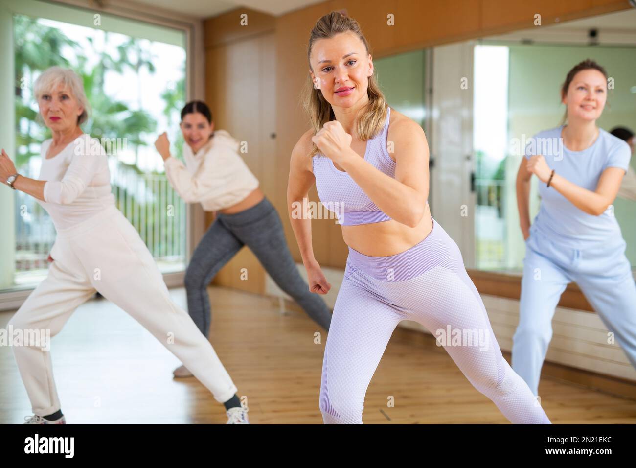 Cheerful energetic women amateur dancers of different ages moving leg ...