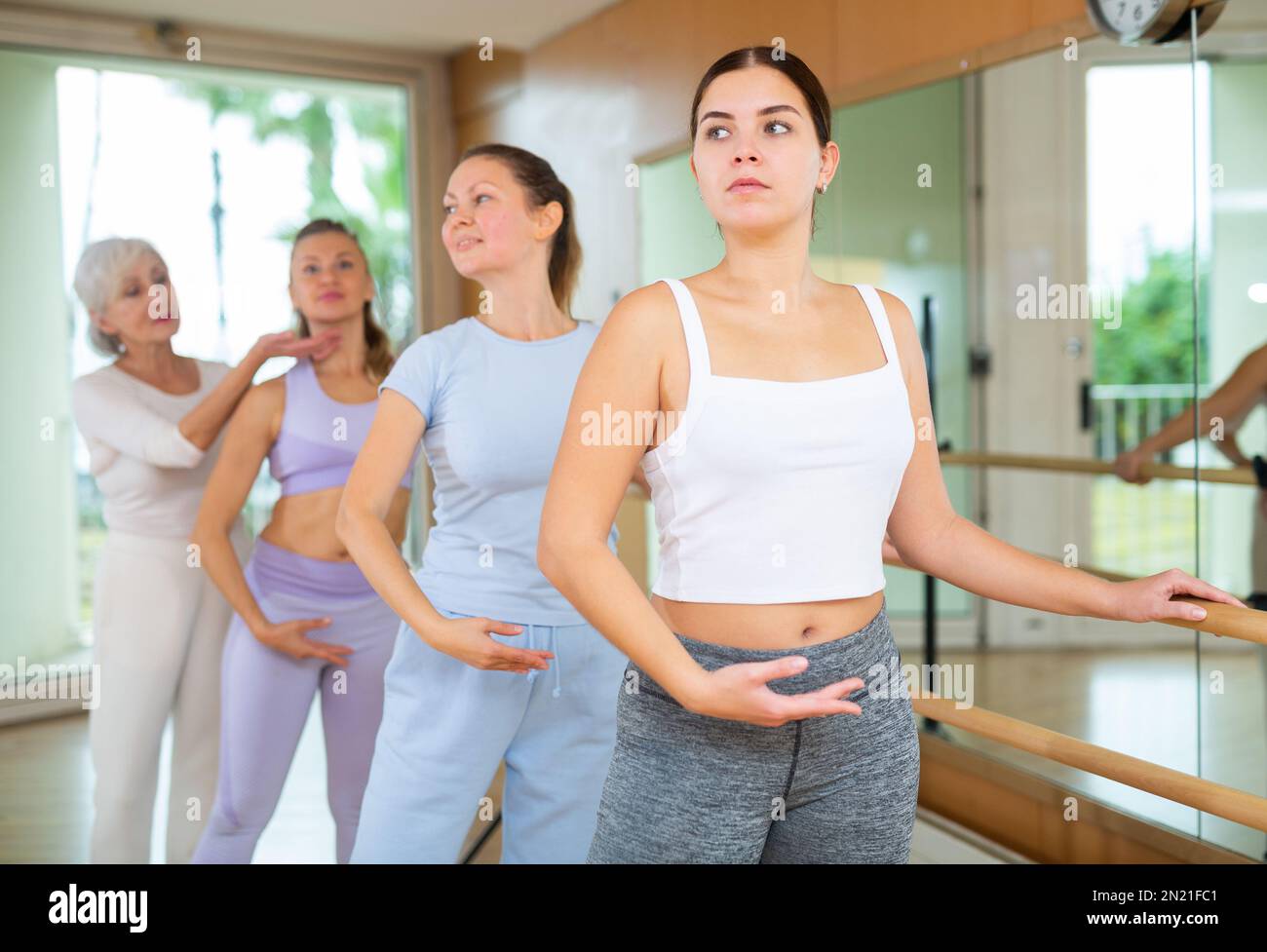 Female ballet instructor adjusting students form in dancing school ...