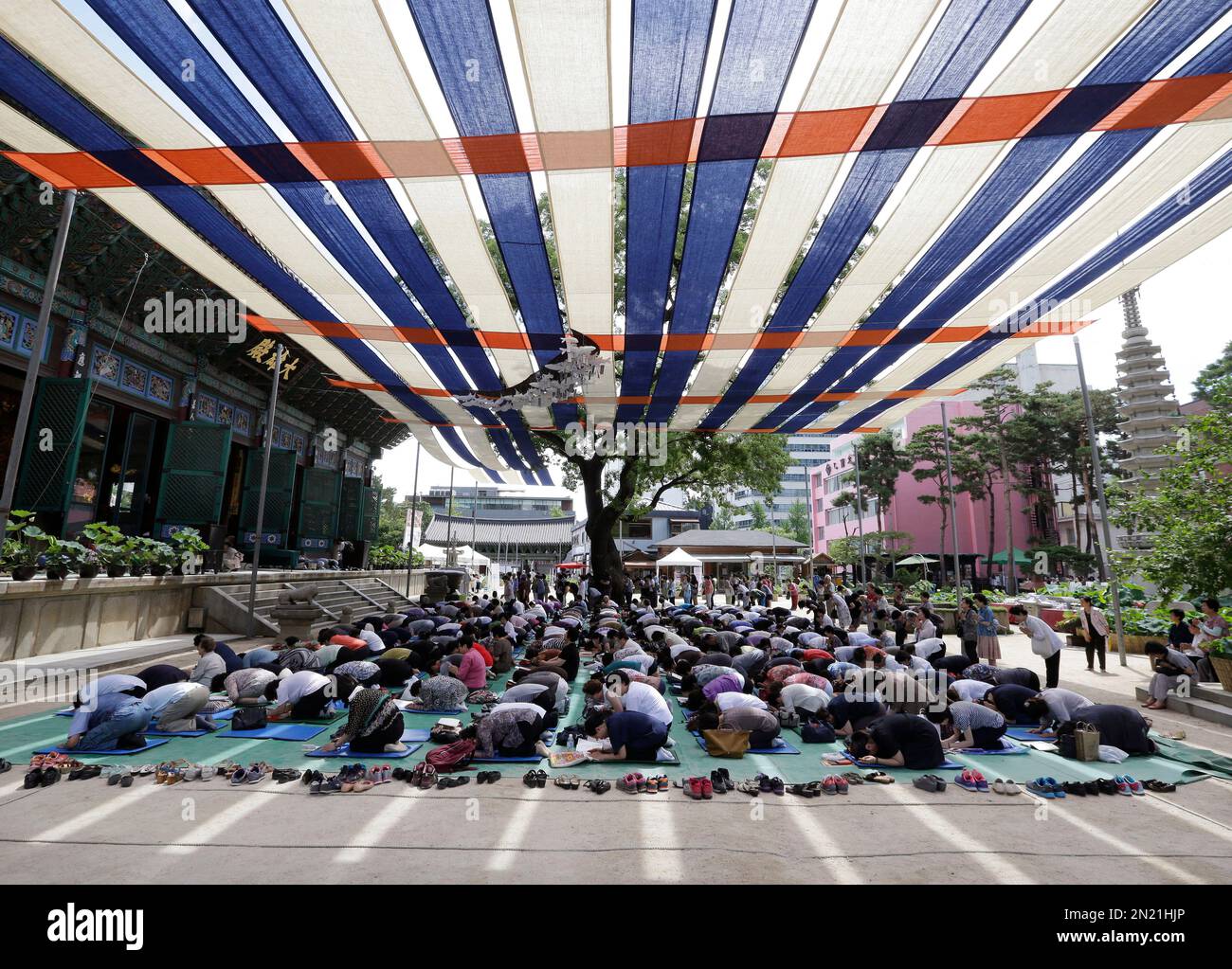 Buddhists pray under the sunshade to avoid the heat during a service at ...