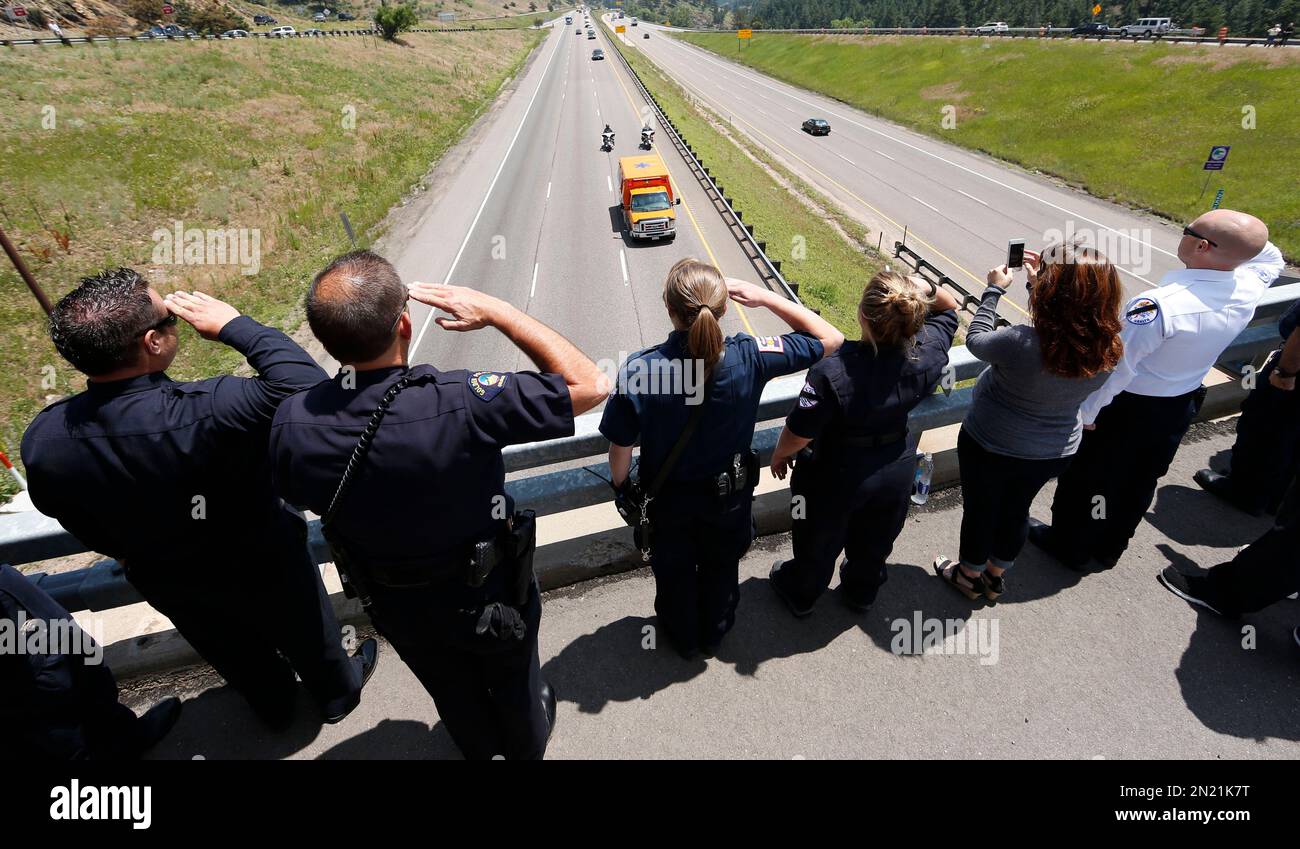 Emergency personnel line up on bridge overpass and salute as a ...