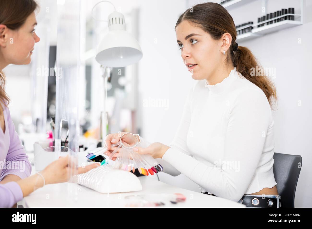 Manicurist demonstrating a palette with lacquer color schemes to a ...