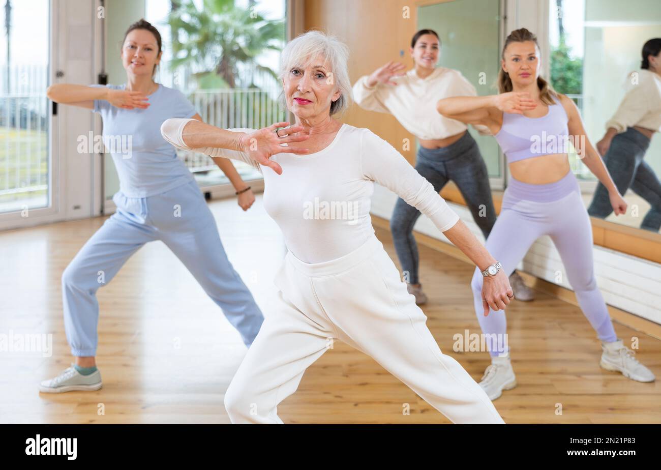 Active positive senior woman performing dance elements during lesson ...