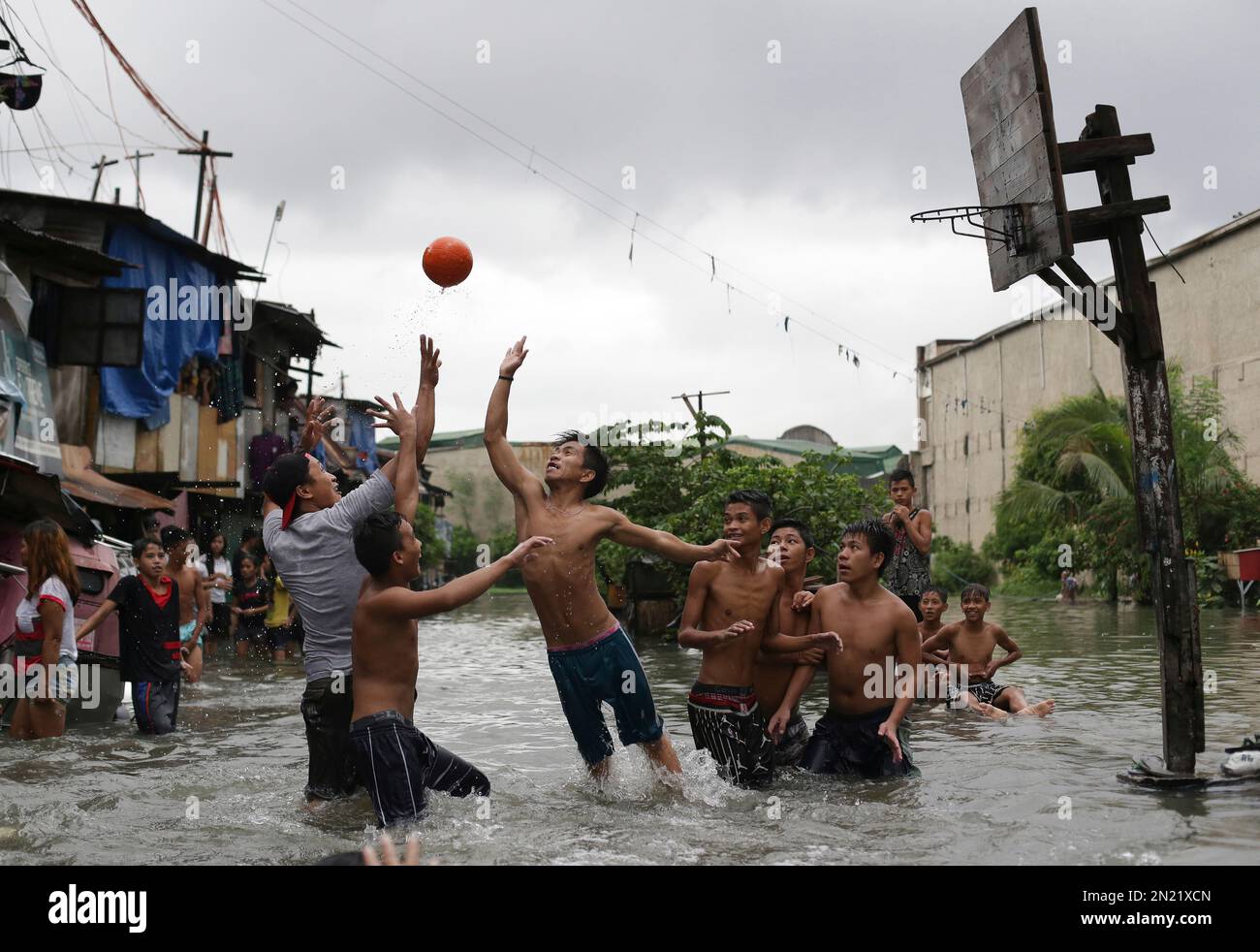 Filipino boys play basketball in floodwaters from a swollen creek at a ...