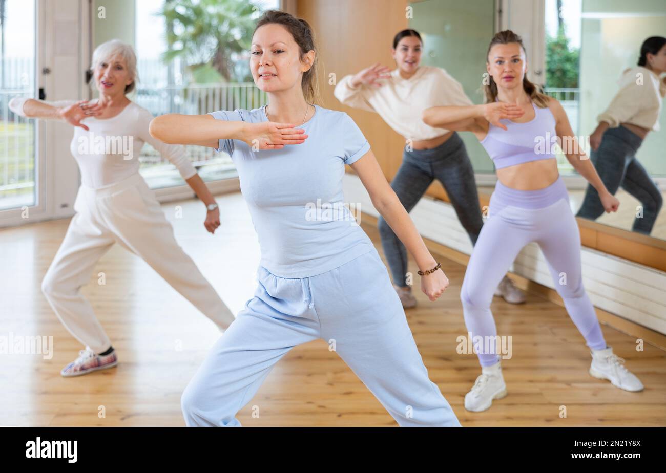 Cheerful energetic female dancers of different ages learning new ...