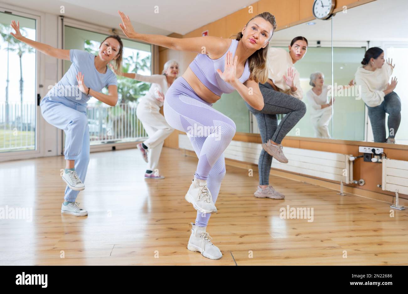 Group of energetic young mature female dancers dancing with knee lift ...