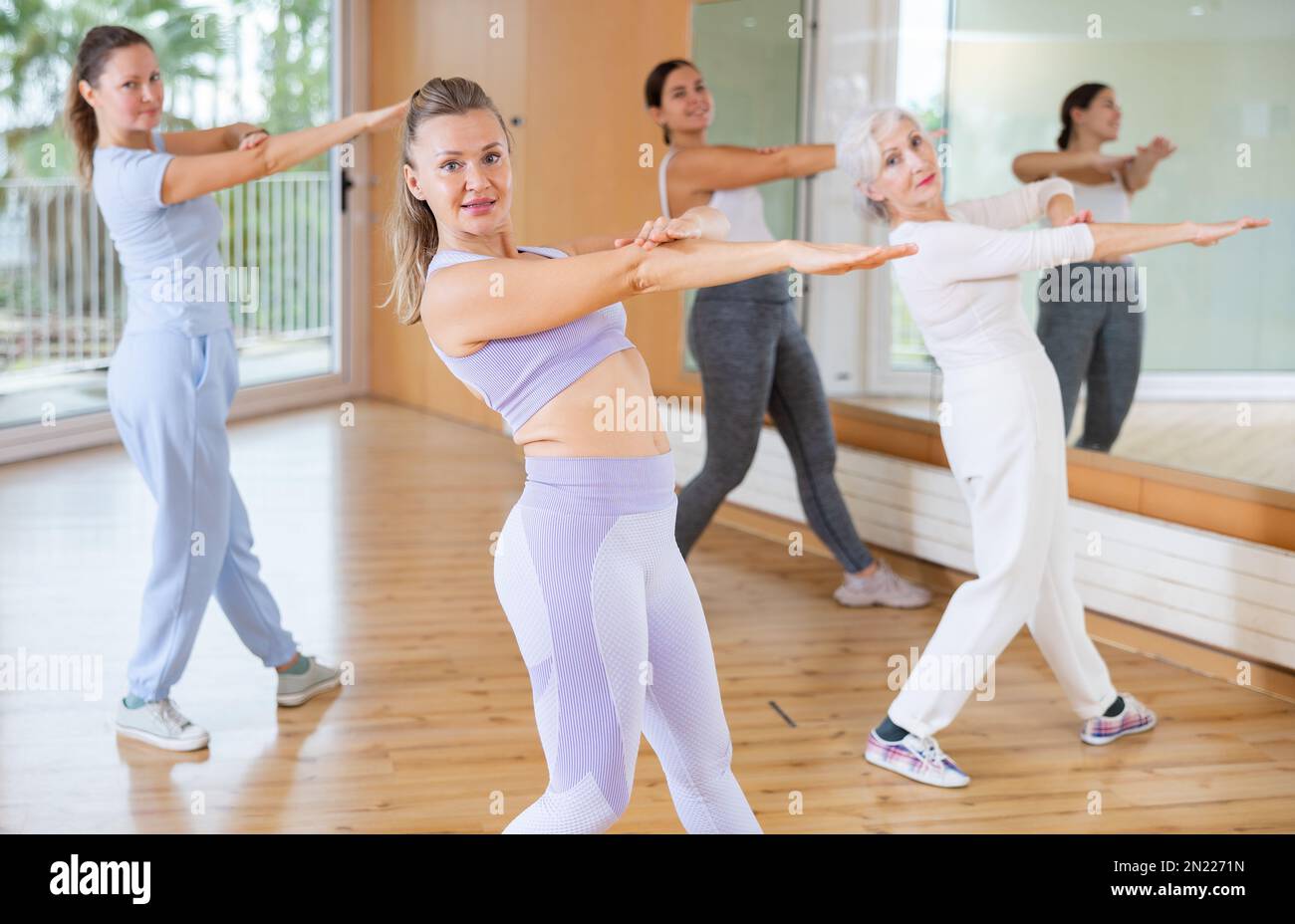 Four active women of different ages performing energetic moves of hands ...