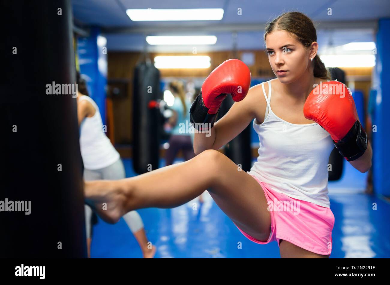 Girl in boxing gloves mastering kicks on punching bag in gym Stock ...