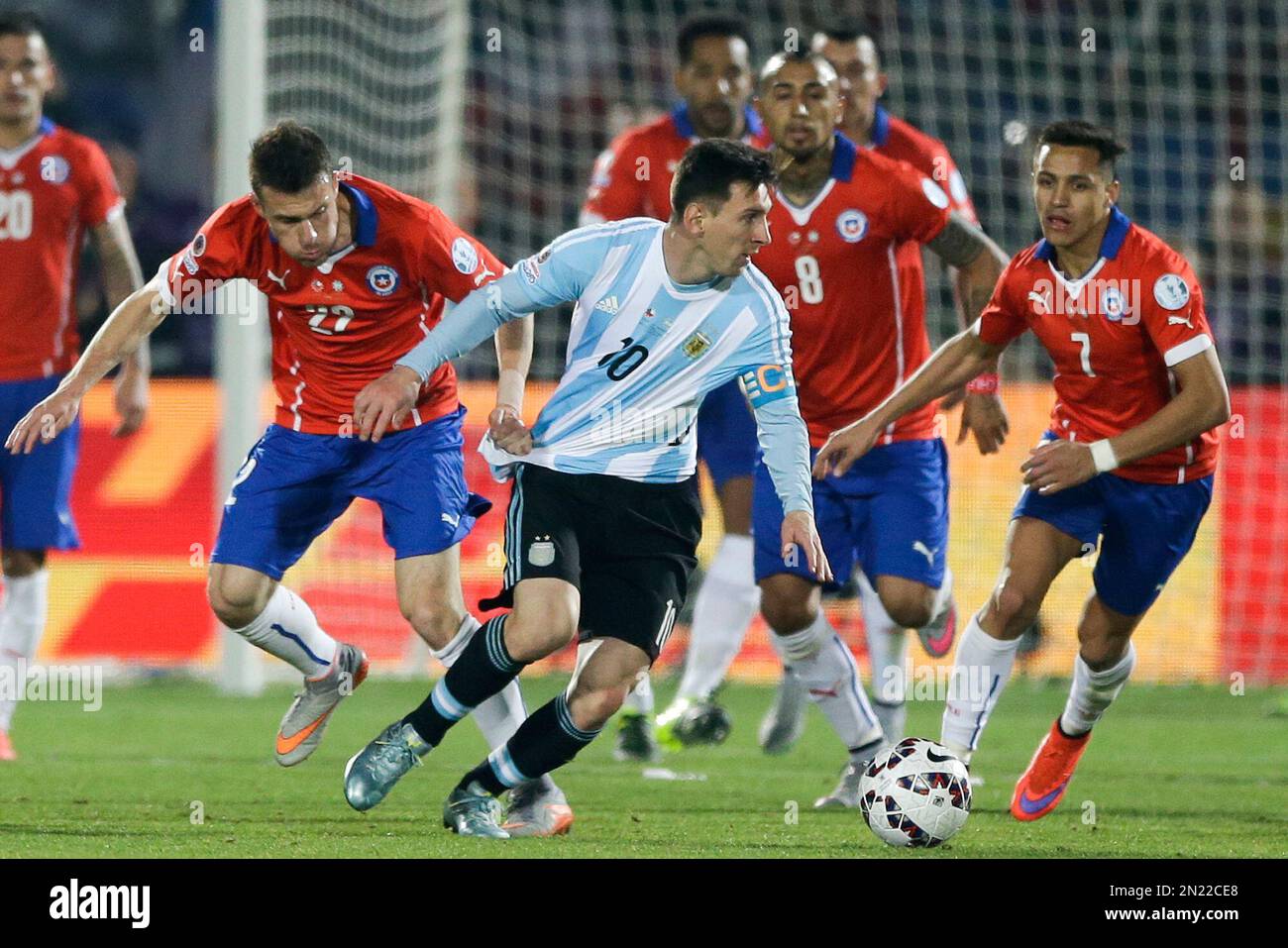 Chile's Angelo Henriquez, left, holds Argentina's Lionel Messi, center ...