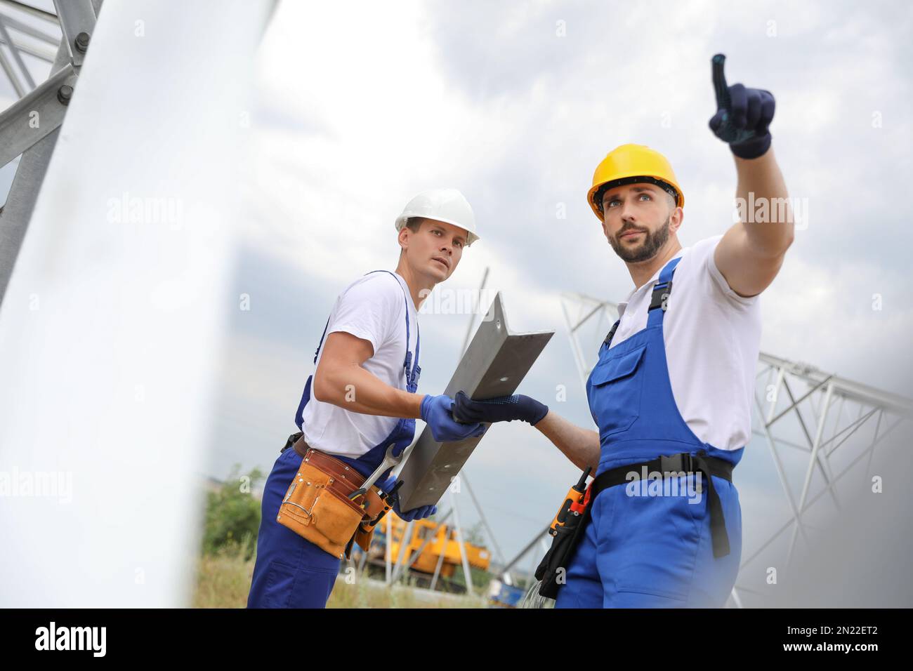 Workers building high voltage tower construction outdoors. Installation ...