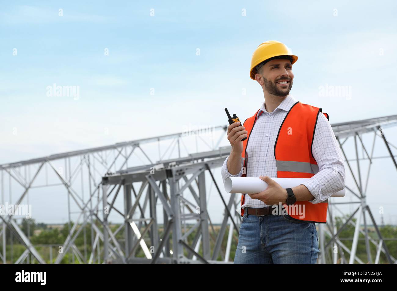 Professional engineer with plan and walkie talkie near high voltage ...