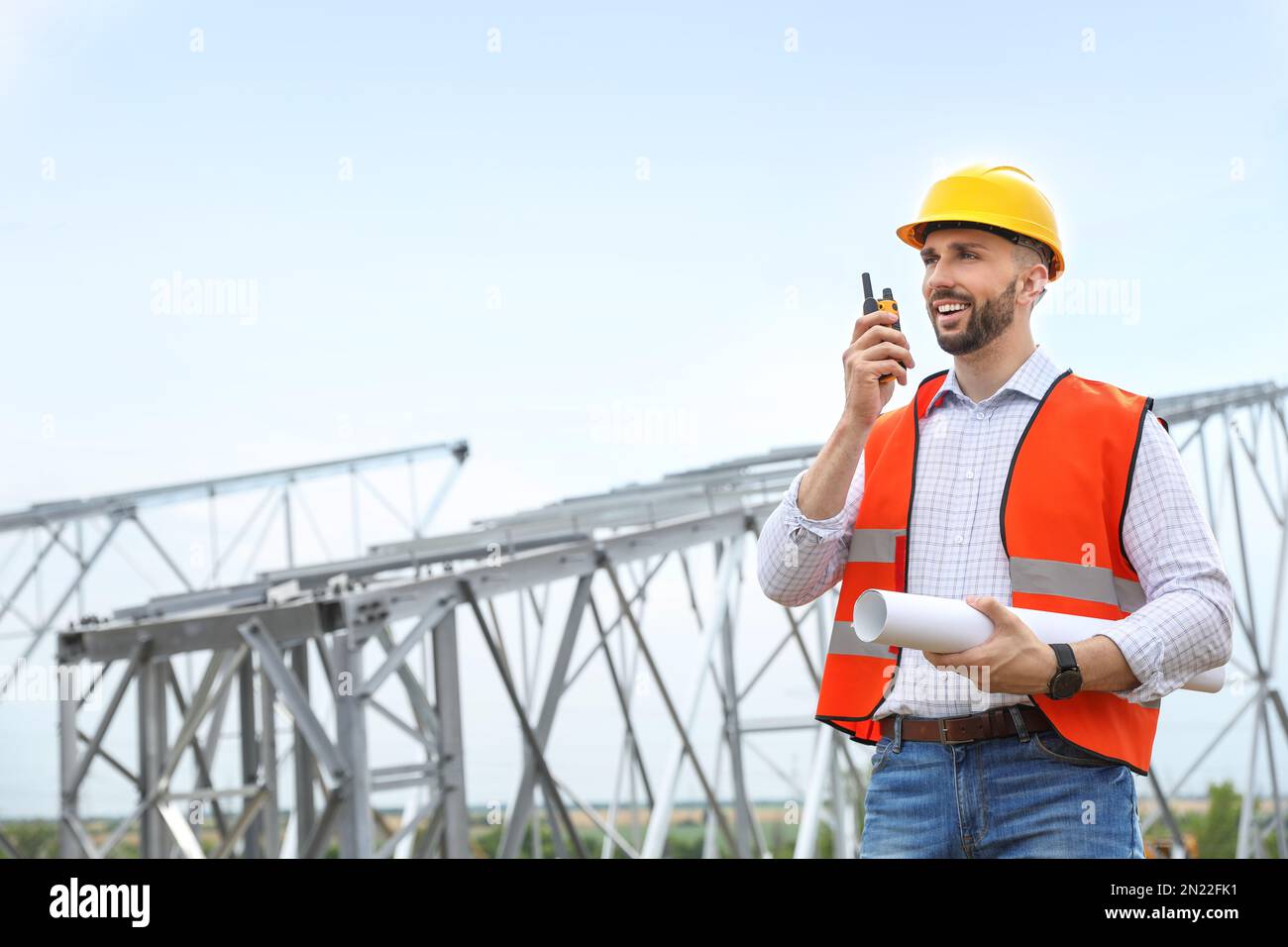 Professional engineer with plan and walkie talkie near high voltage ...