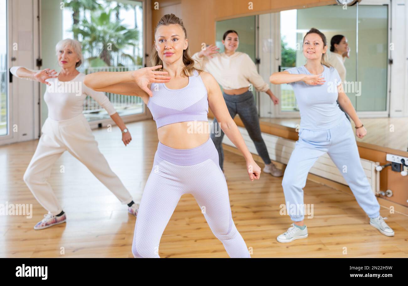 Positive women of different ages performing modern dancing exercises in ...