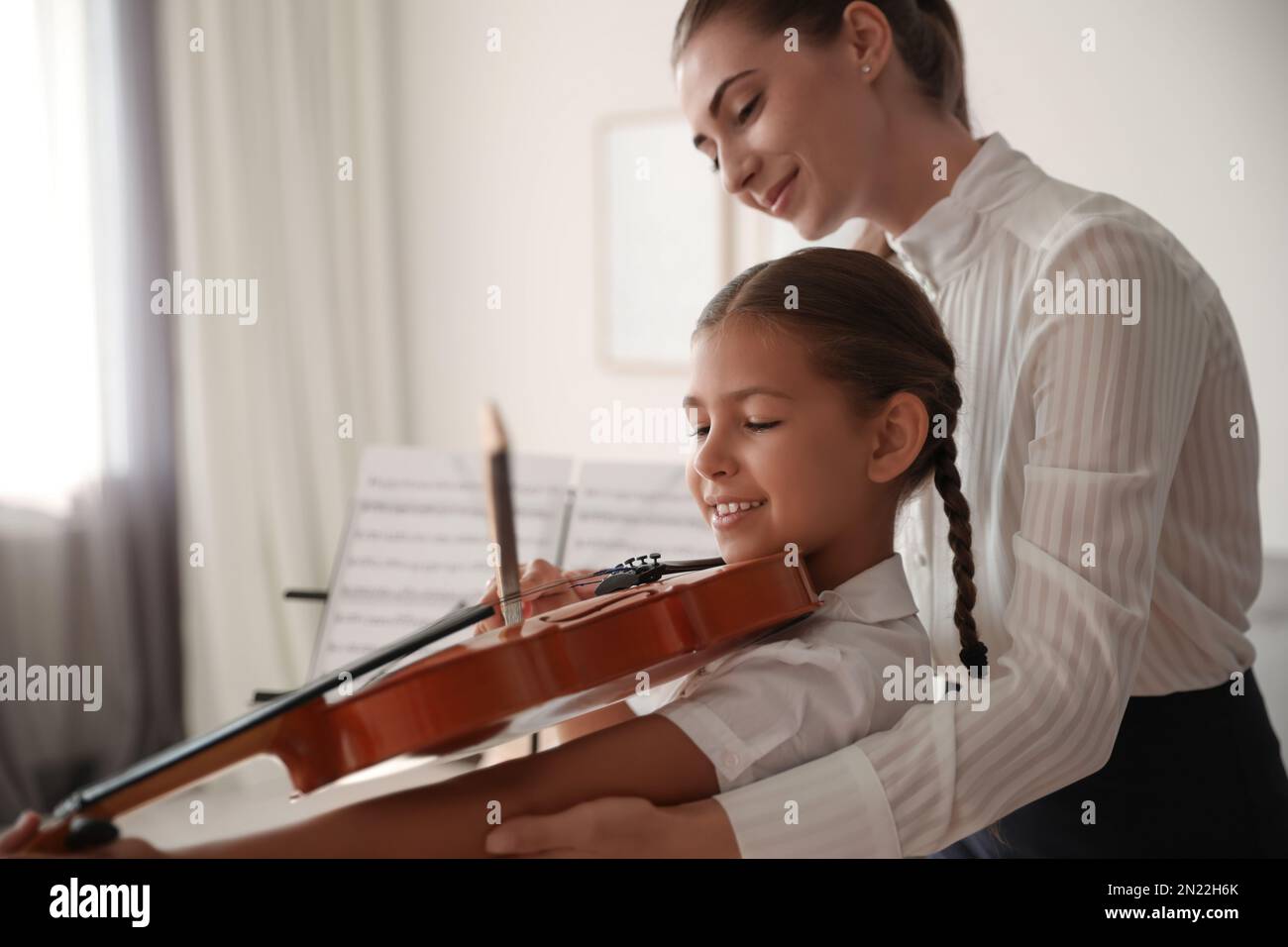 Young woman teaching little girl to play violin indoors Stock Photo - Alamy