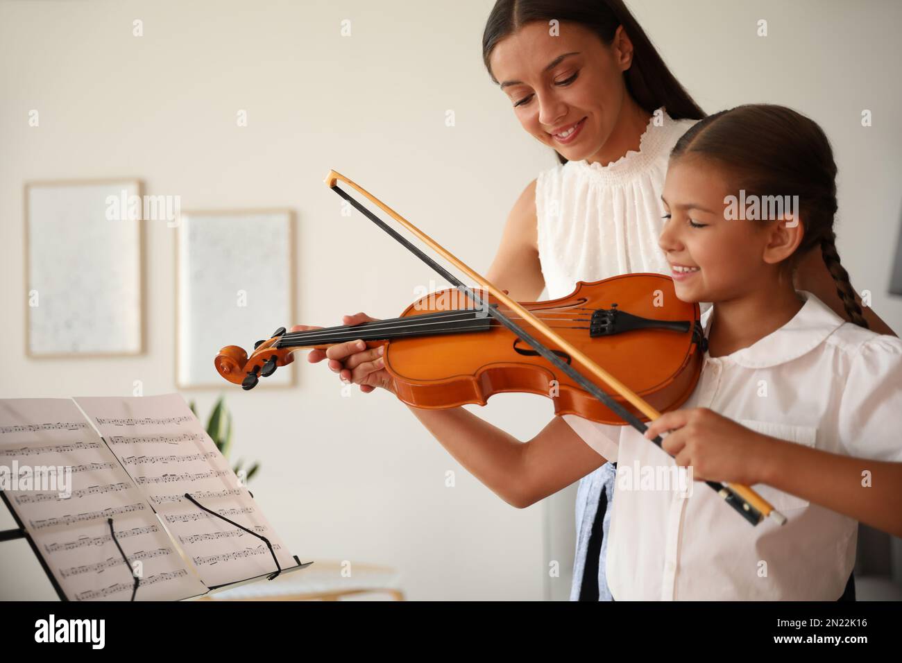 Young woman teaching little girl to play violin indoors Stock Photo - Alamy