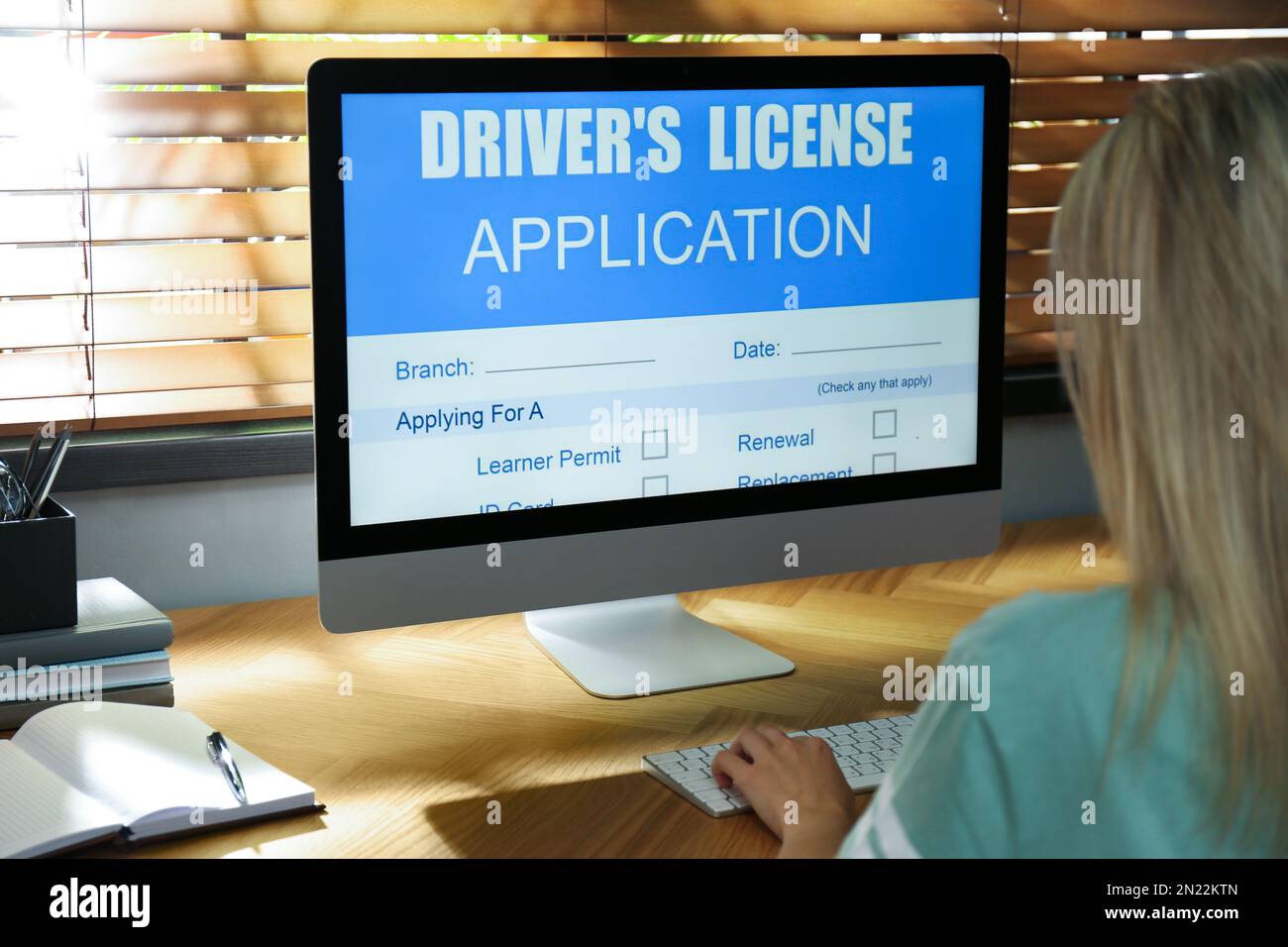Woman using computer to fill driver's license application form at table in office, closeup Stock ...